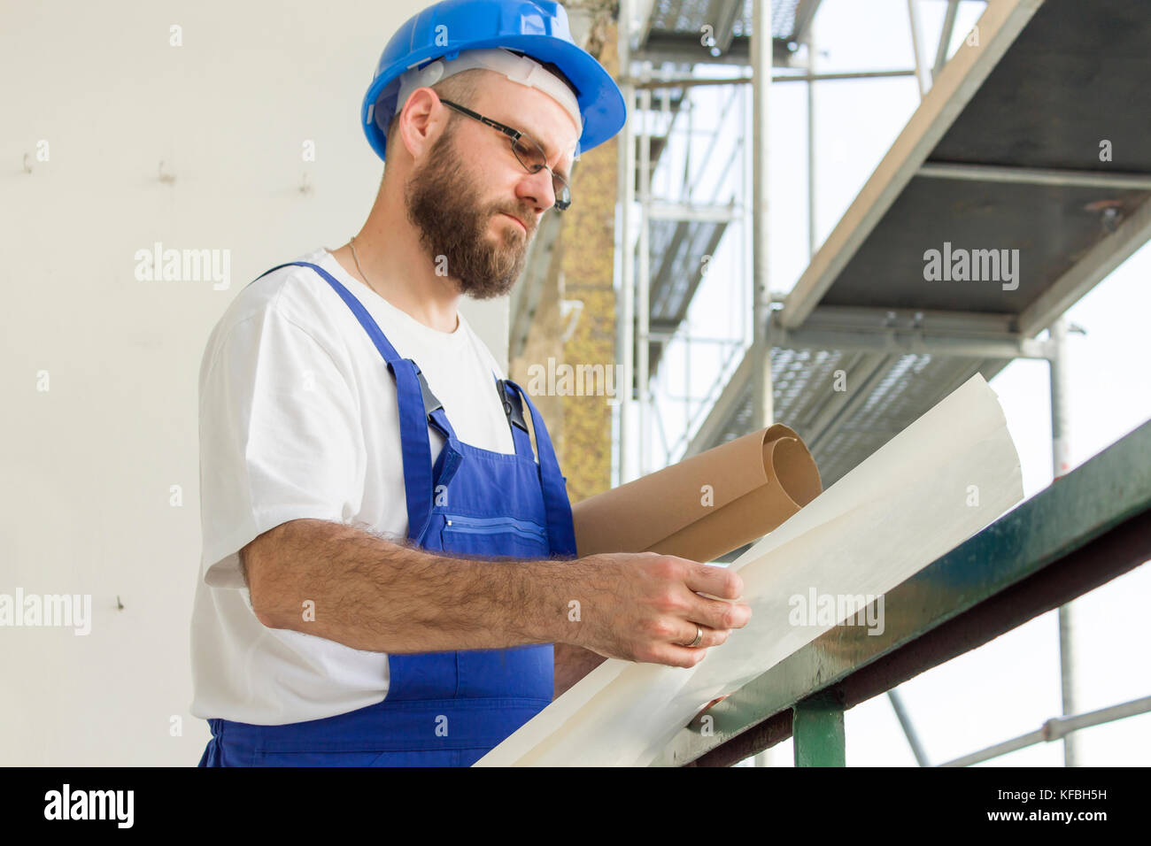 Construction worker in working outfit and in helmet stands at high ...