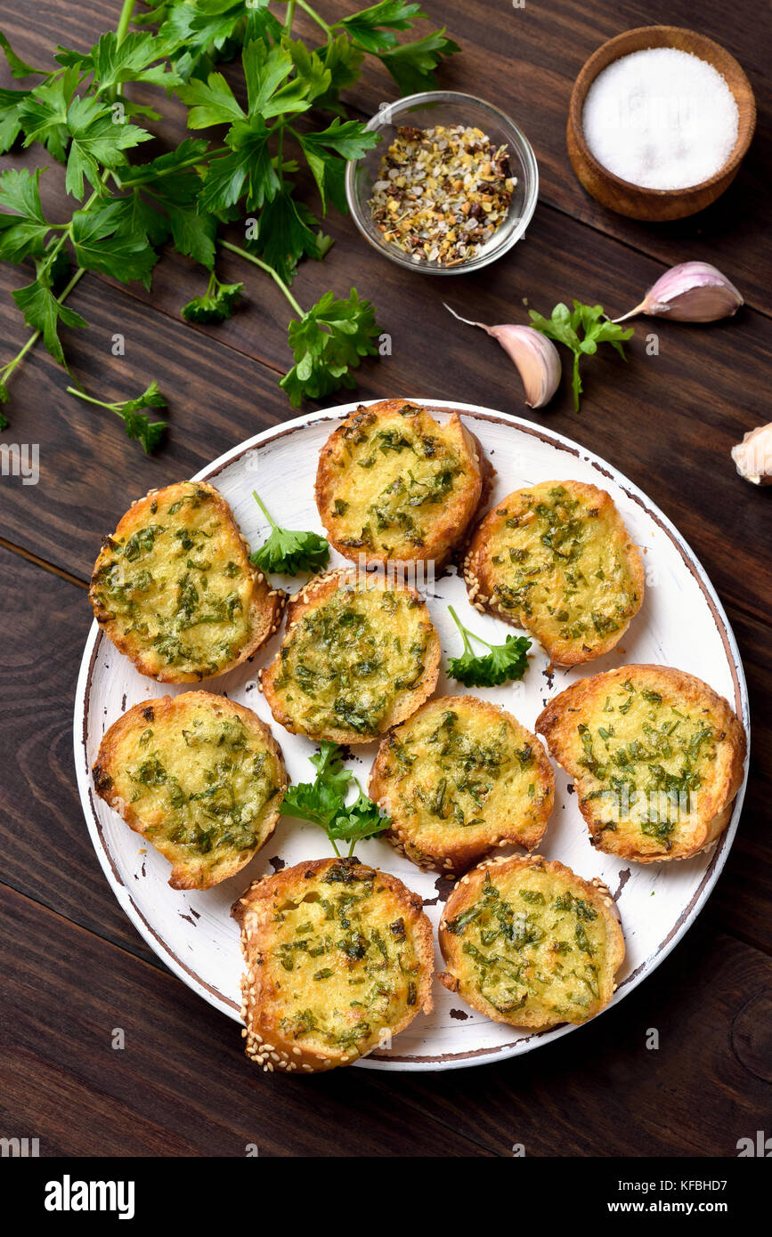 Toasts with cheese and greens on plate over wooden table, top view ...