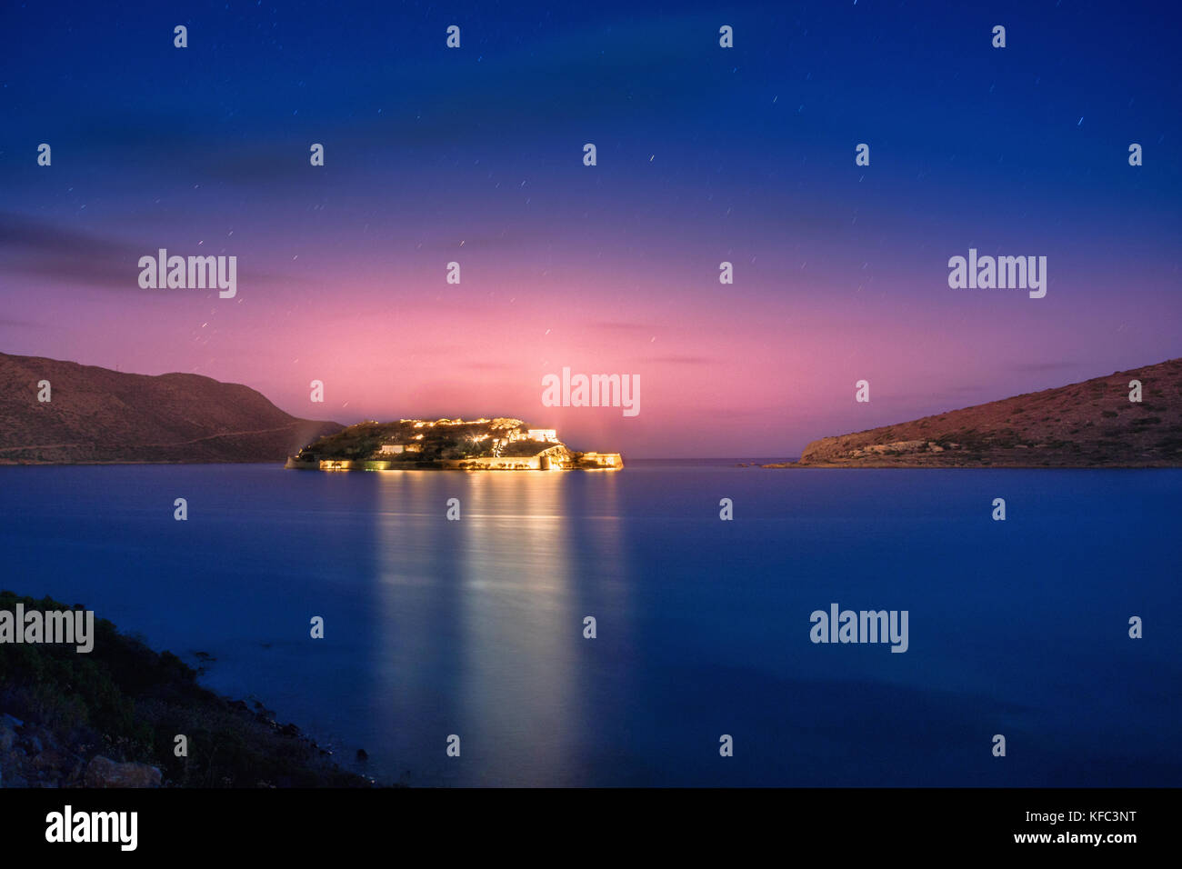 View of the island of Spinalonga at night with nice clouds and calm sea ...