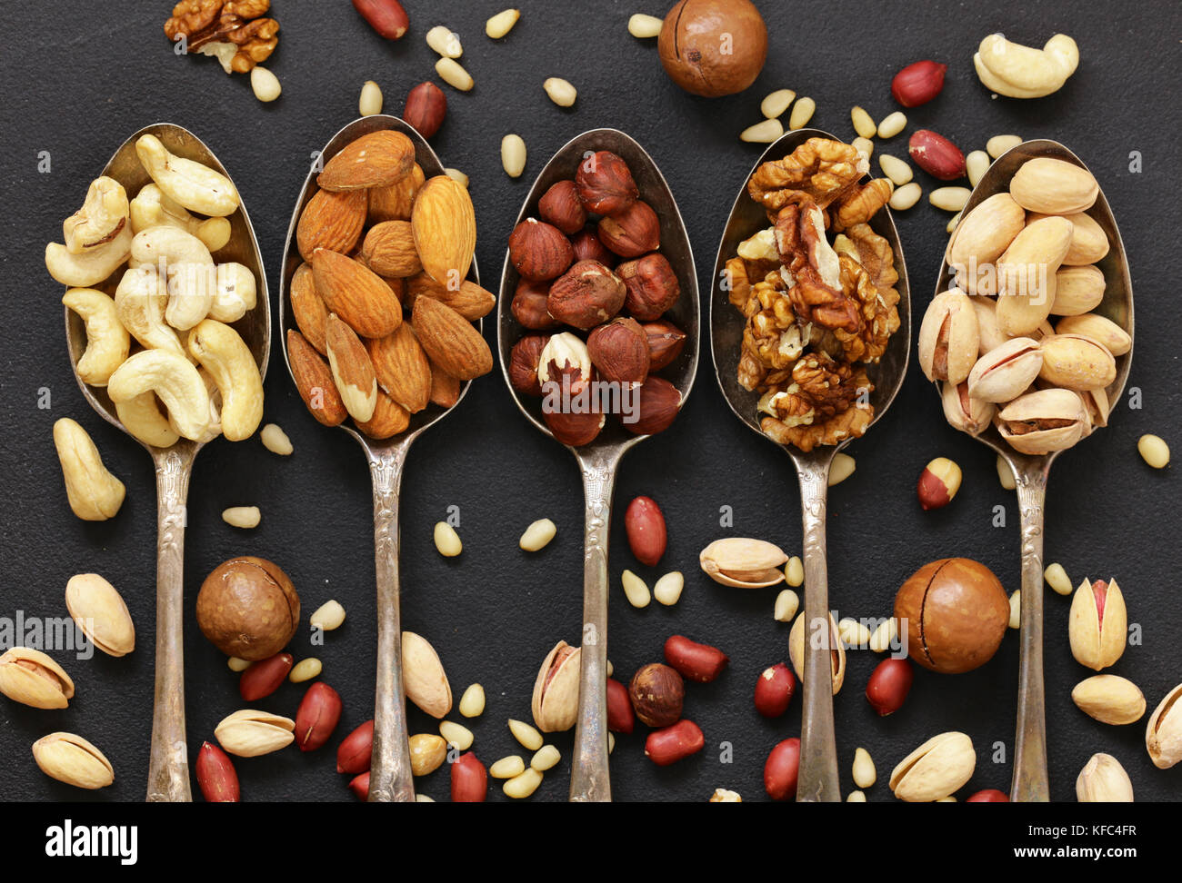 various kinds of nuts (cedar, cashew, hazelnuts, walnuts) in spoons ...
