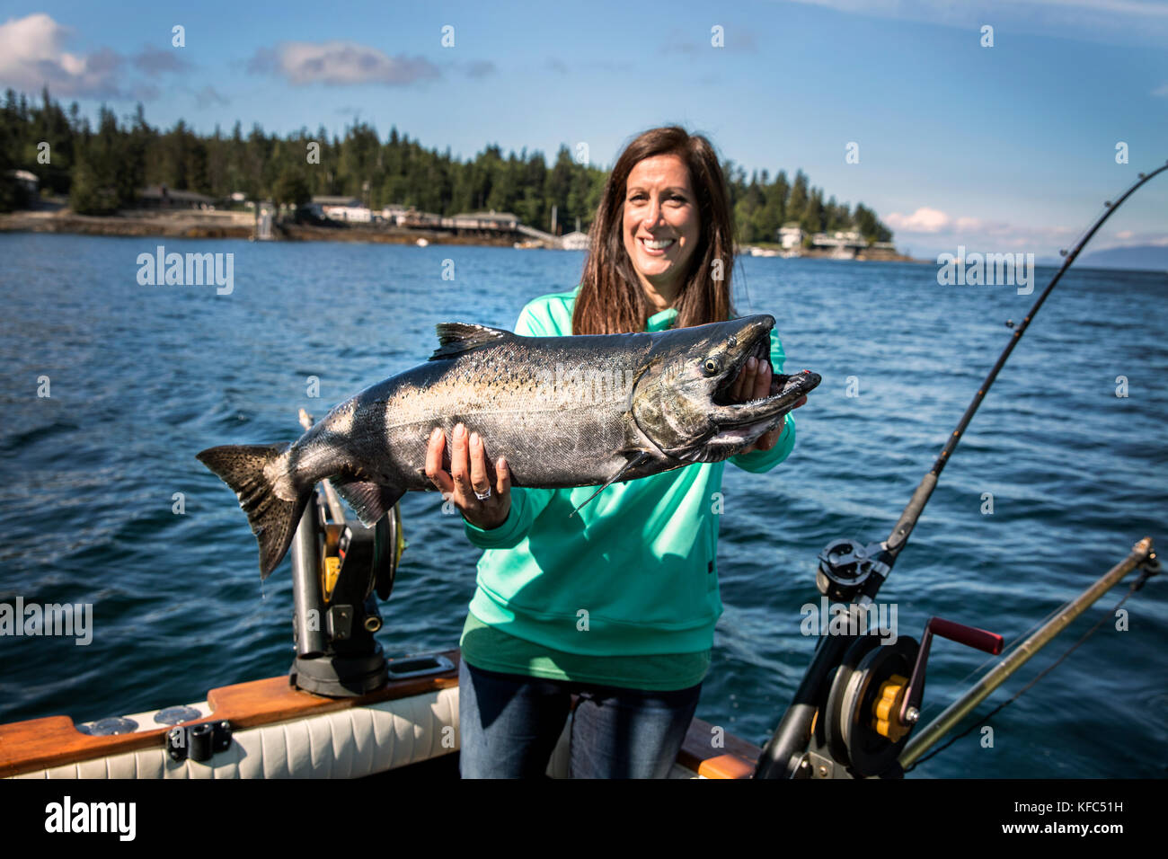 USA, Alaska, Ketchikan, a female fisherman shows off her catch while ...