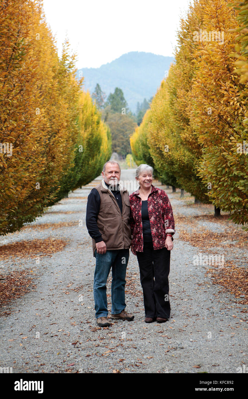 USA, Oregon, Medford, Cal and Judy Schmidt stand among the trees on ...