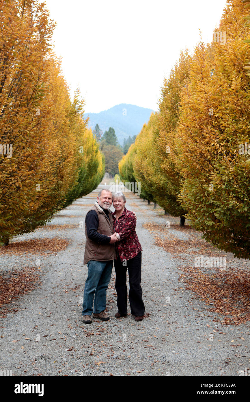 USA, Oregon, Medford, Cal and Judy Schmidt stand among the trees on ...