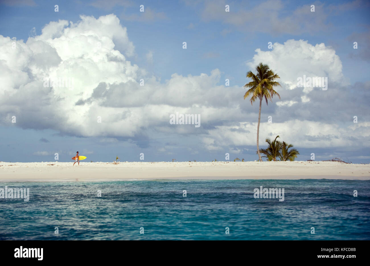 INDONESIA, Mentawai Islands, Kandui Resort, lone surfer walking on a ...