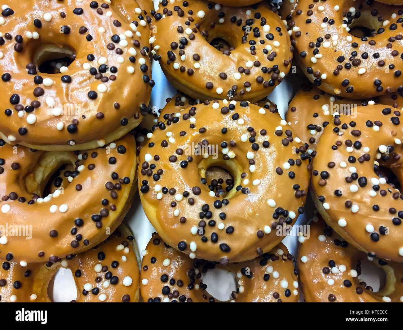 Fresh sweet donuts in chocolate glaze with colored confectionery powder ...