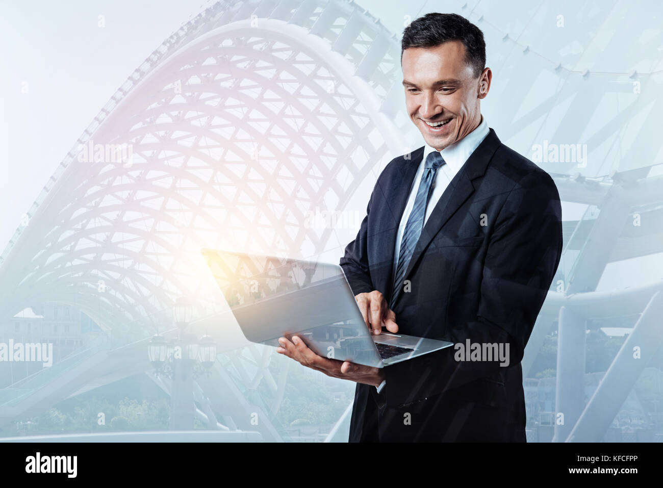 Cheerful smart businessman using a laptop Stock Photo - Alamy