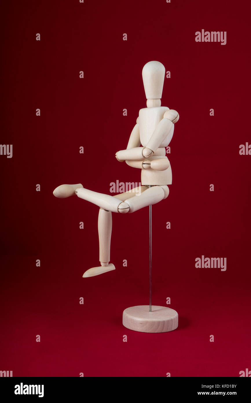 a wooden dummy in sitting position with a red background Stock Photo ...