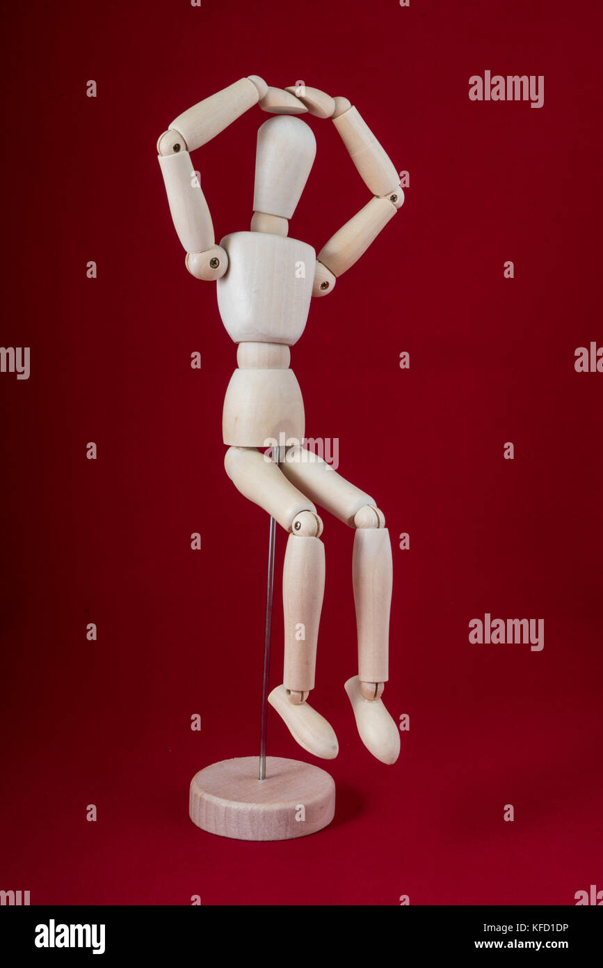 a wooden dummy in sitting position with a red background Stock Photo ...
