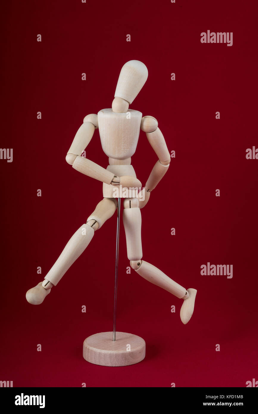 a wooden dummy posing for dance with a red background Stock Photo - Alamy