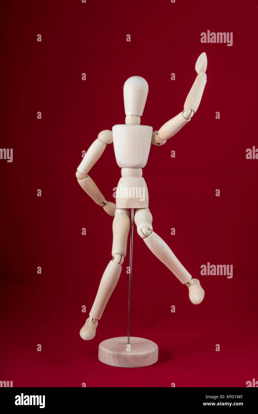 a wooden dummy posing for dance with a red background Stock Photo - Alamy