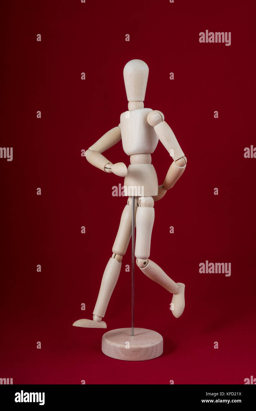 a wooden dummy posing for dance with a red background Stock Photo - Alamy