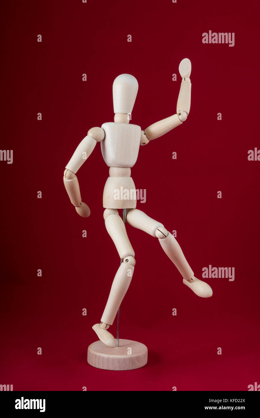 a wooden dummy posing for dance with a red background Stock Photo - Alamy