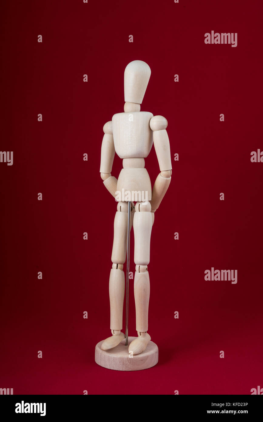 a wooden dummy posing on a red background Stock Photo - Alamy