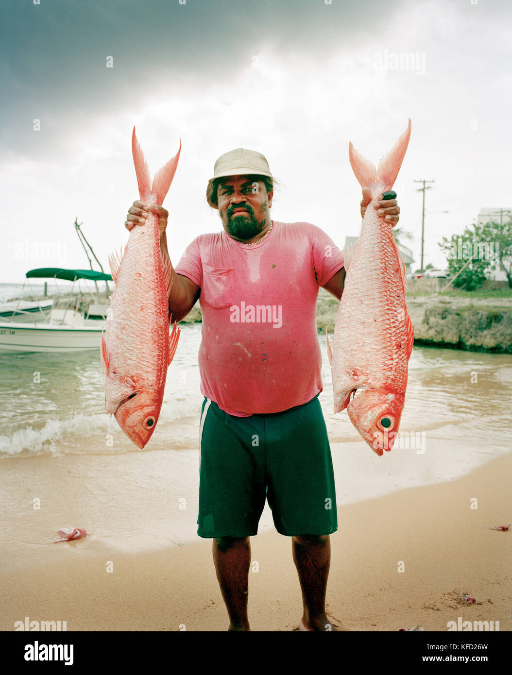 CAYMAN ISLANDS, Grand Cayman, fisherman holding two red snapper caught ...