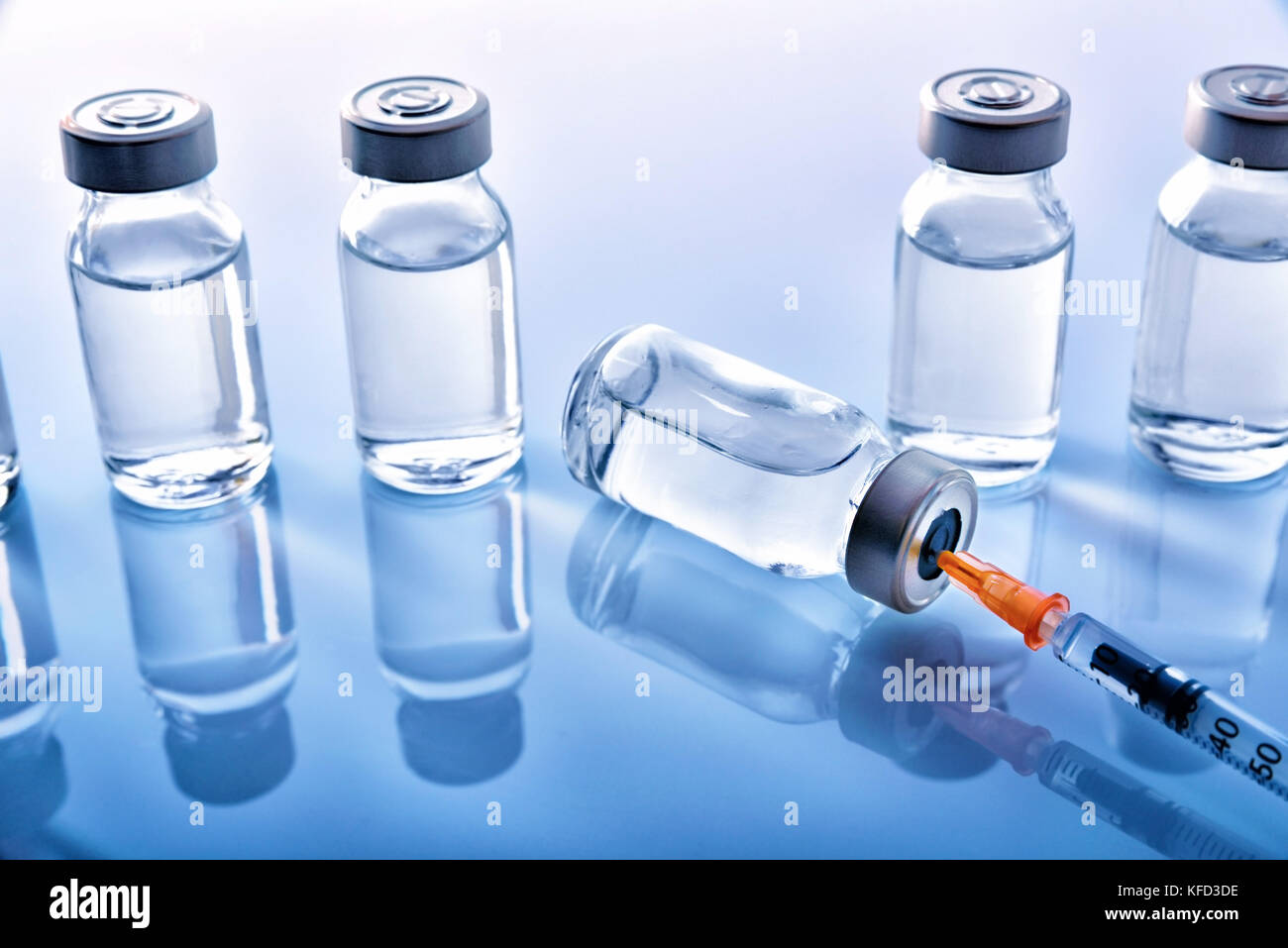 Group of vials with medication and punctured syringe on blue ...