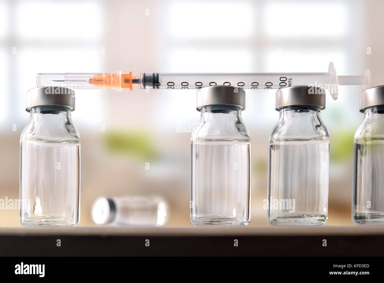 Row of vials with medication and syringe on white methacrylate table ...