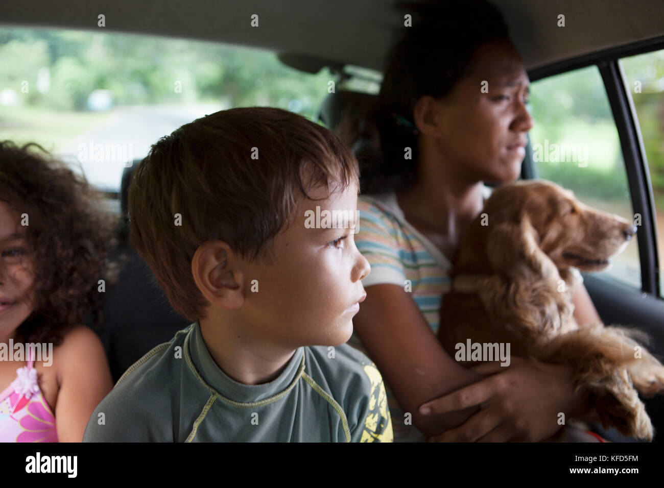 FRENCH POLYNESIA, Moorea Island. Kids riding in the back of a car with ...