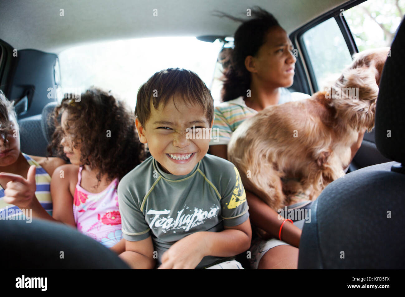 FRENCH POLYNESIA, Moorea Island. Kids riding in the back of a car with ...