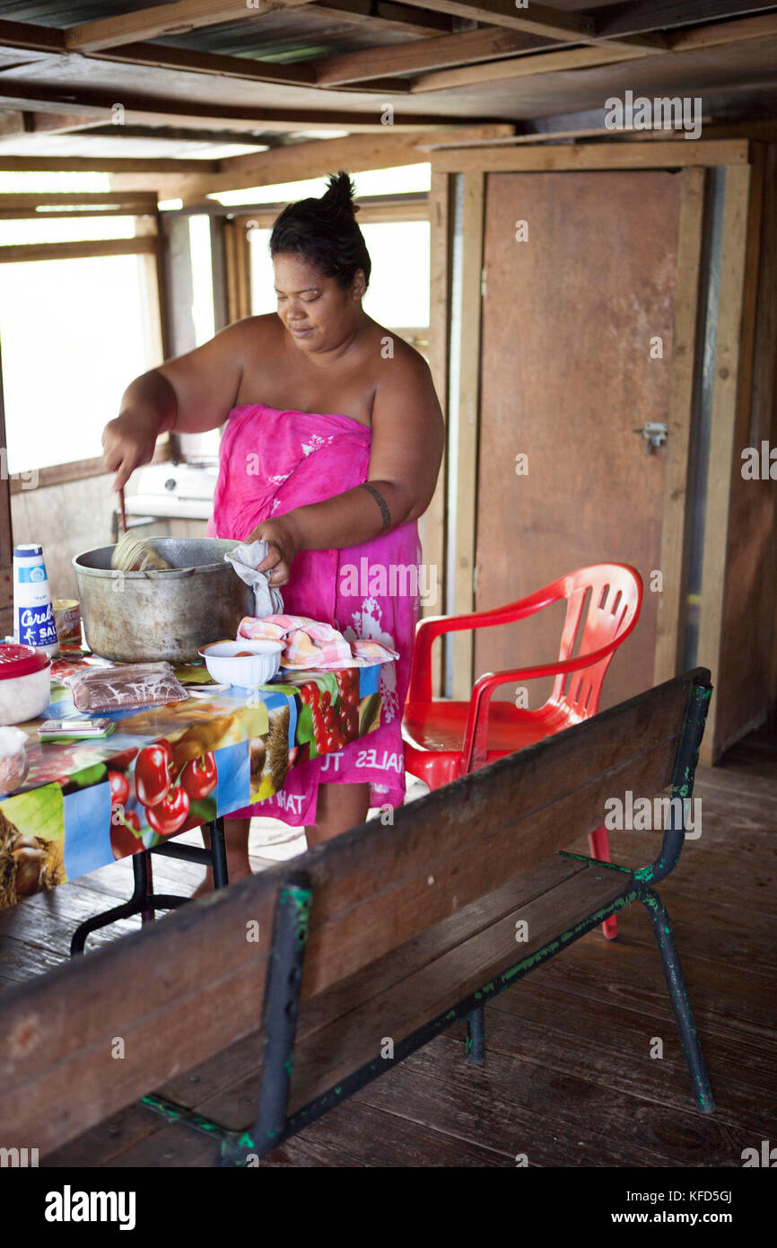 FRENCH POLYNESIA, Moorea. A woman wearing a sarong and cooking in her ...