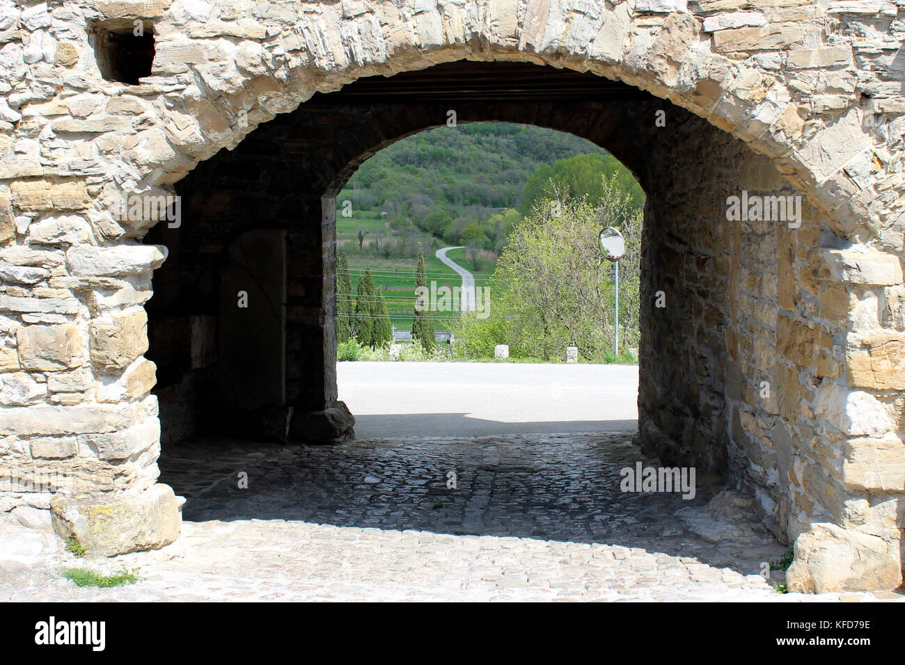 Traditional stone wall opening towards main road with small winding ...