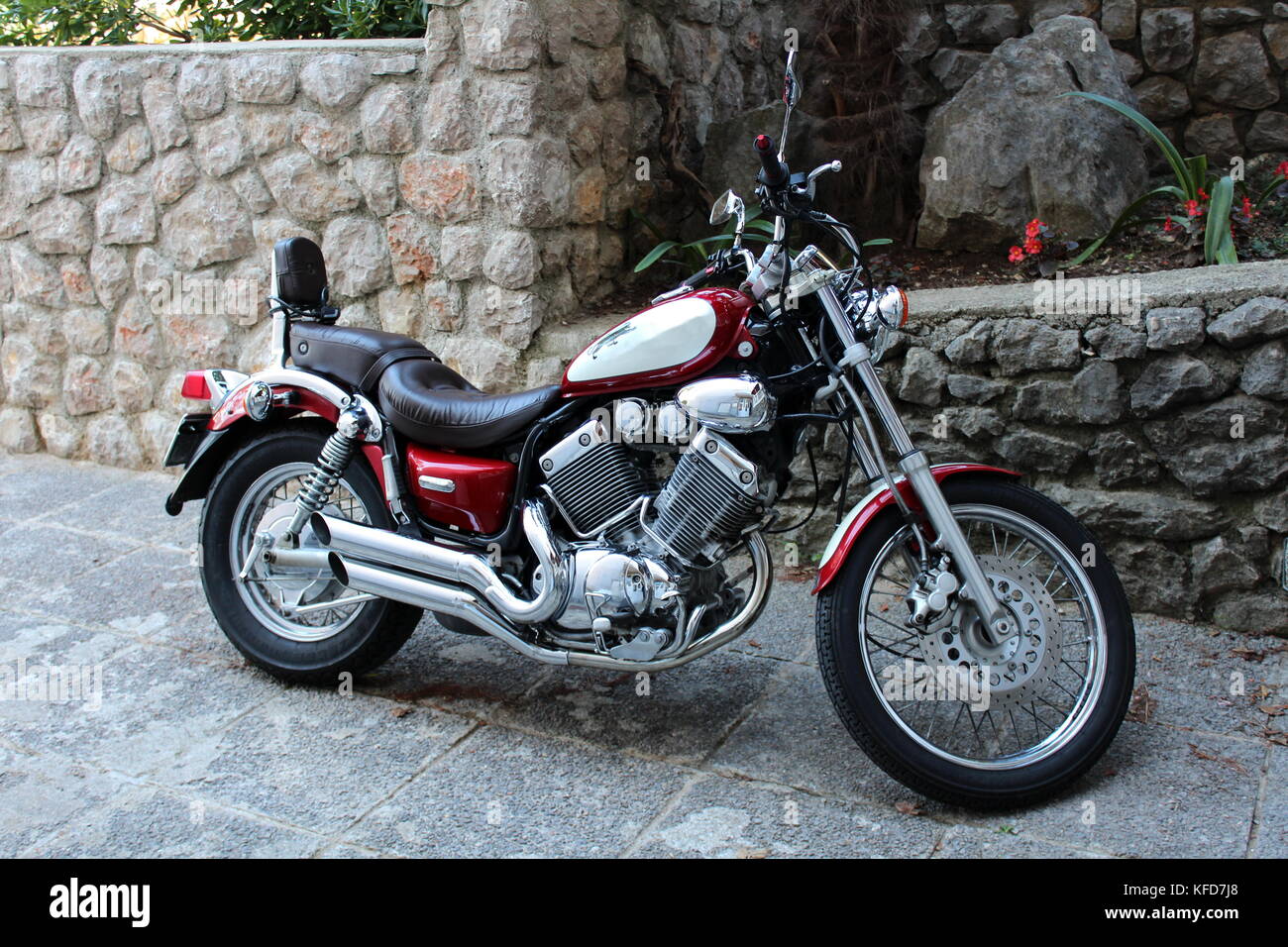 Modern new and polished red and chrome chopper parked in front of stone ...