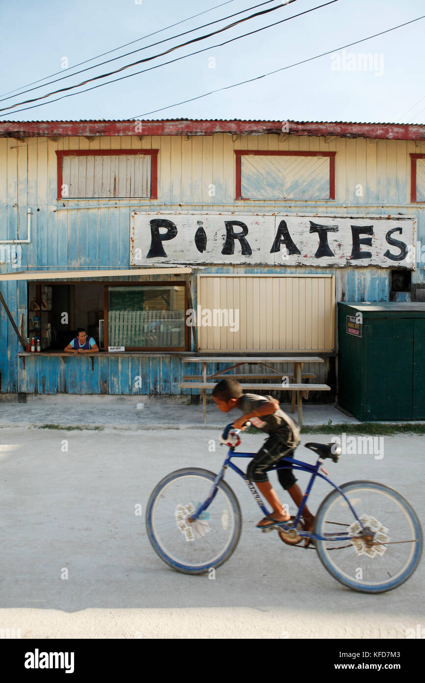 BELIZE, Caye Caulker, a boy rides his bike past pirates restaurant ...
