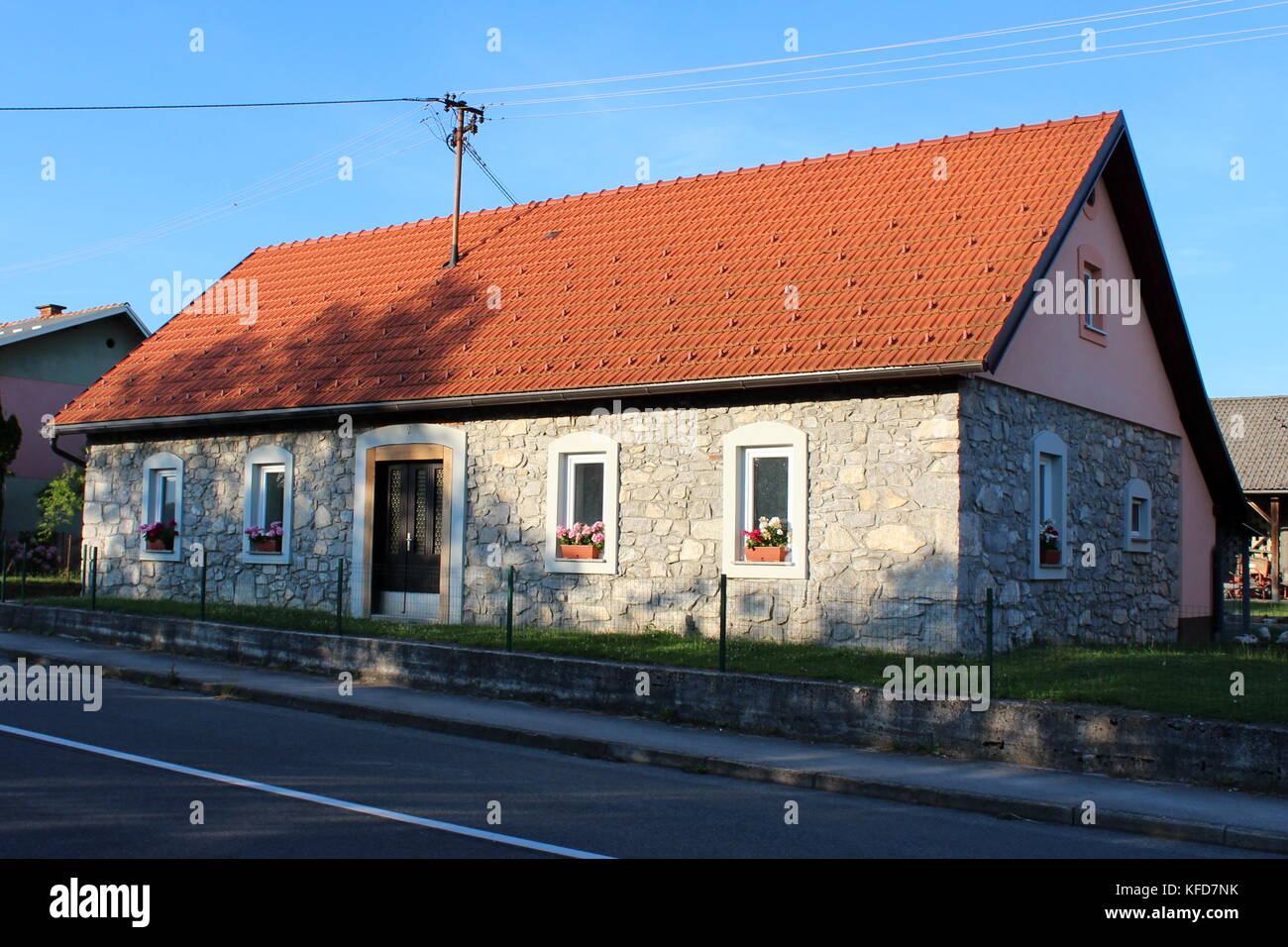Renovated small stone house with new red roof at sunset with tree ...