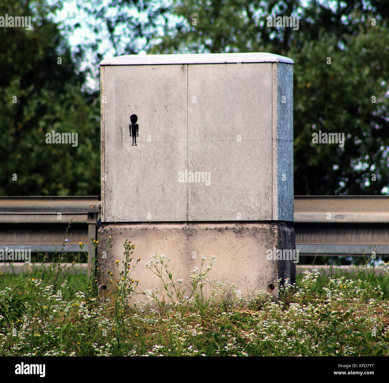 Small black alien looking graffiti painted on grey electrical box put ...