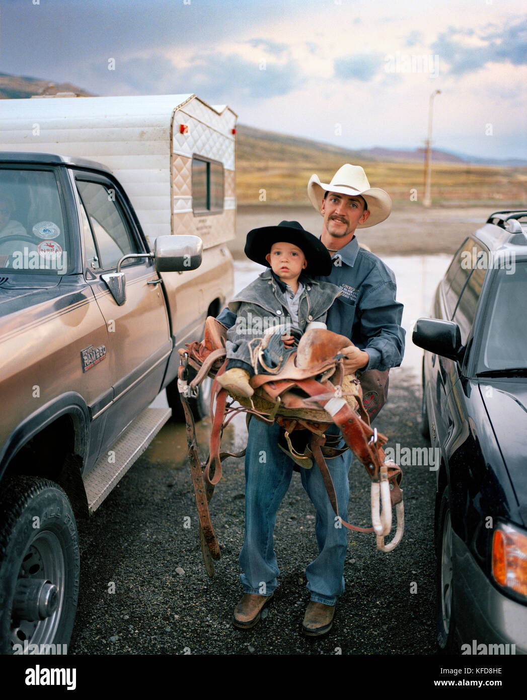 USA, Wyoming, Saddle Bronc Cowboy holding his son, portrait, Cody Rodeo ...