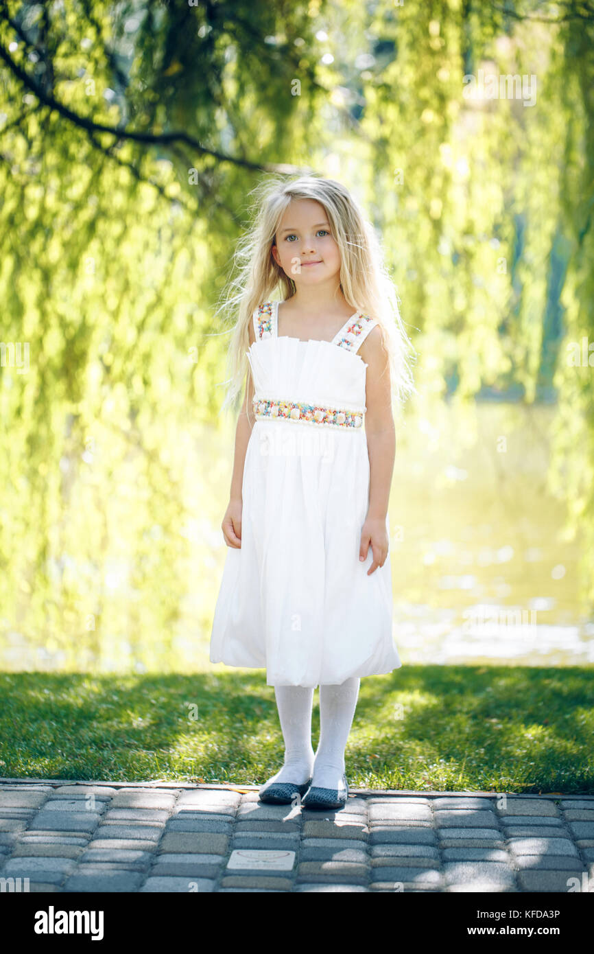 Cute little blonde girl is backlit against the background of water and ...