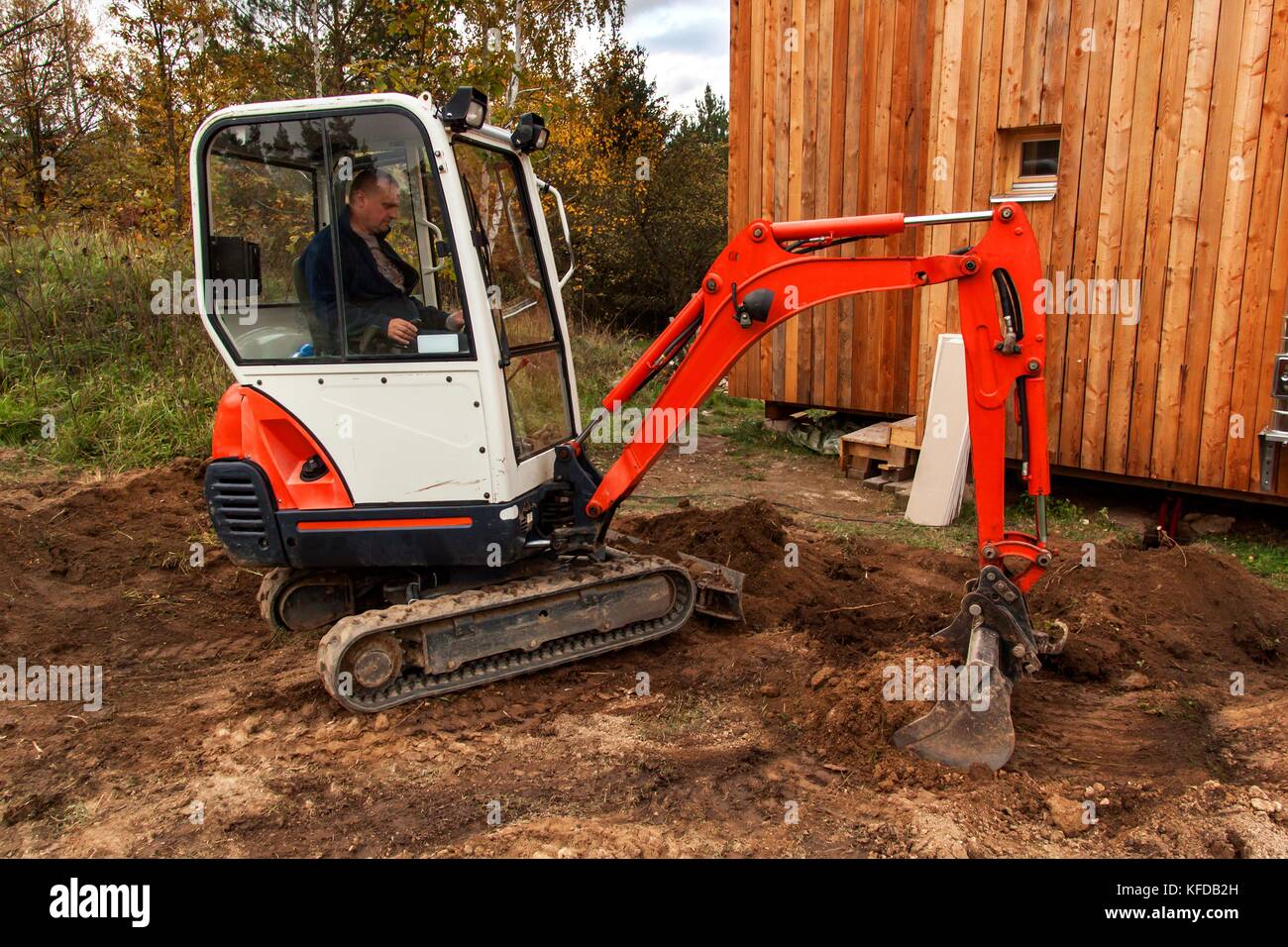 Mini excavator on construction site. Excavator regulates the terrain ...