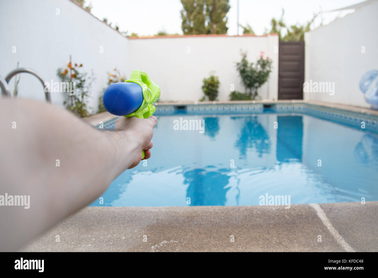 Crop shot of hand holding colorful water gun and aiming on background ...