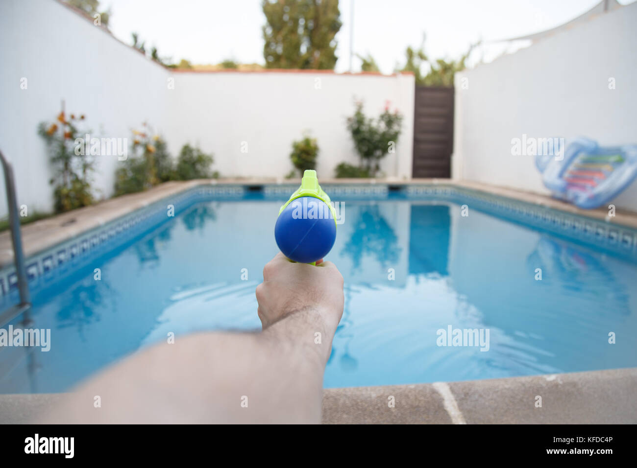 Crop shot of hand holding colorful water gun and aiming on background ...