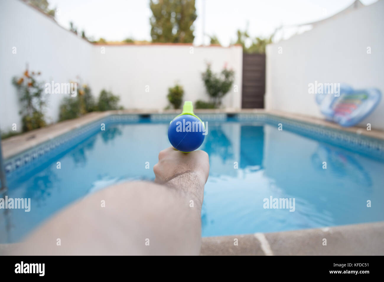 Crop shot of hand holding colorful water gun and aiming on background ...
