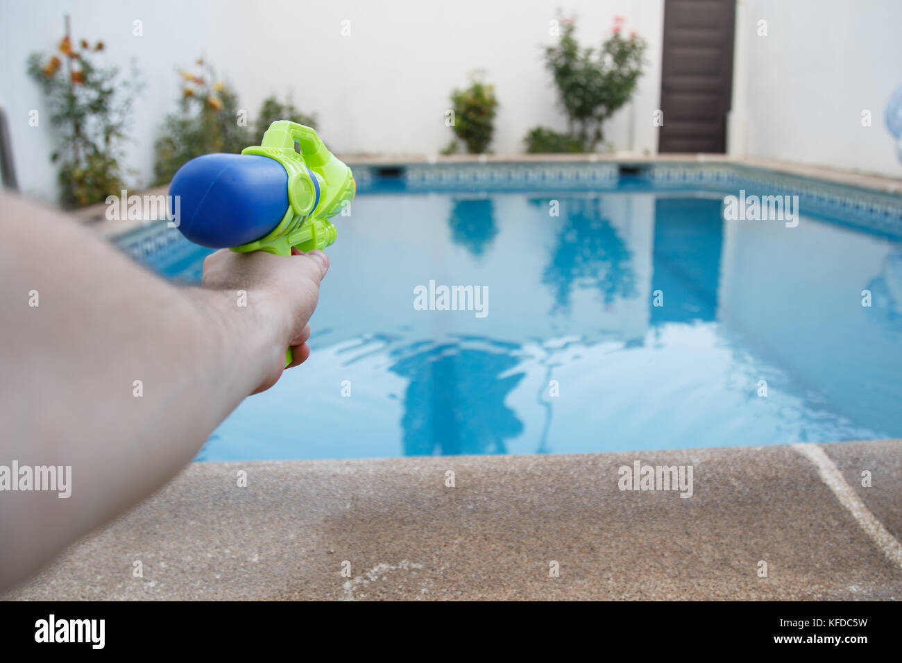 Crop shot of hand holding colorful water gun and aiming on background ...