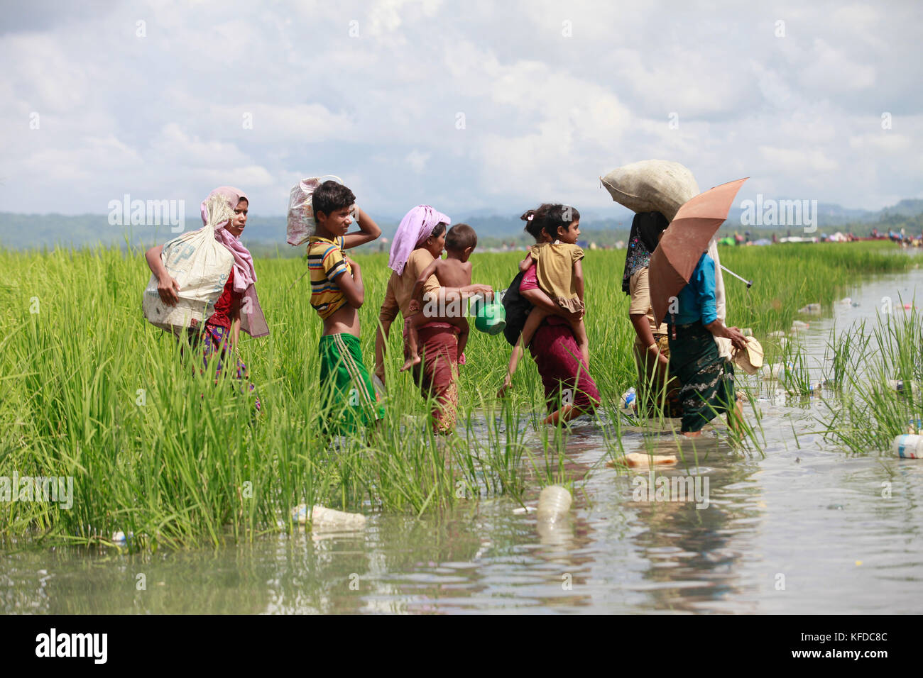 Newly arrived Rohingya Muslims wade through water carrying their ...