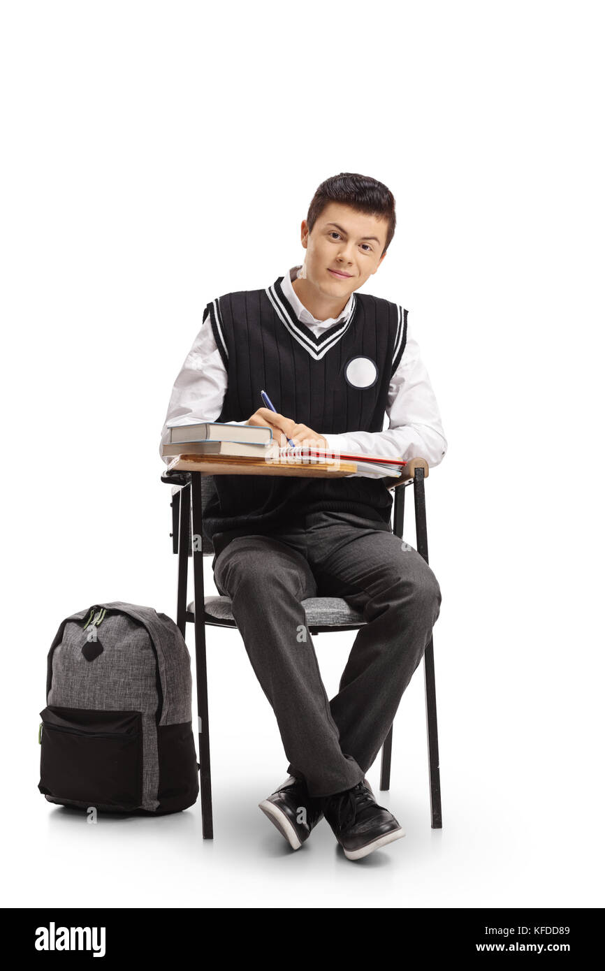Teen student seated in a school chair taking notes and looking at the ...