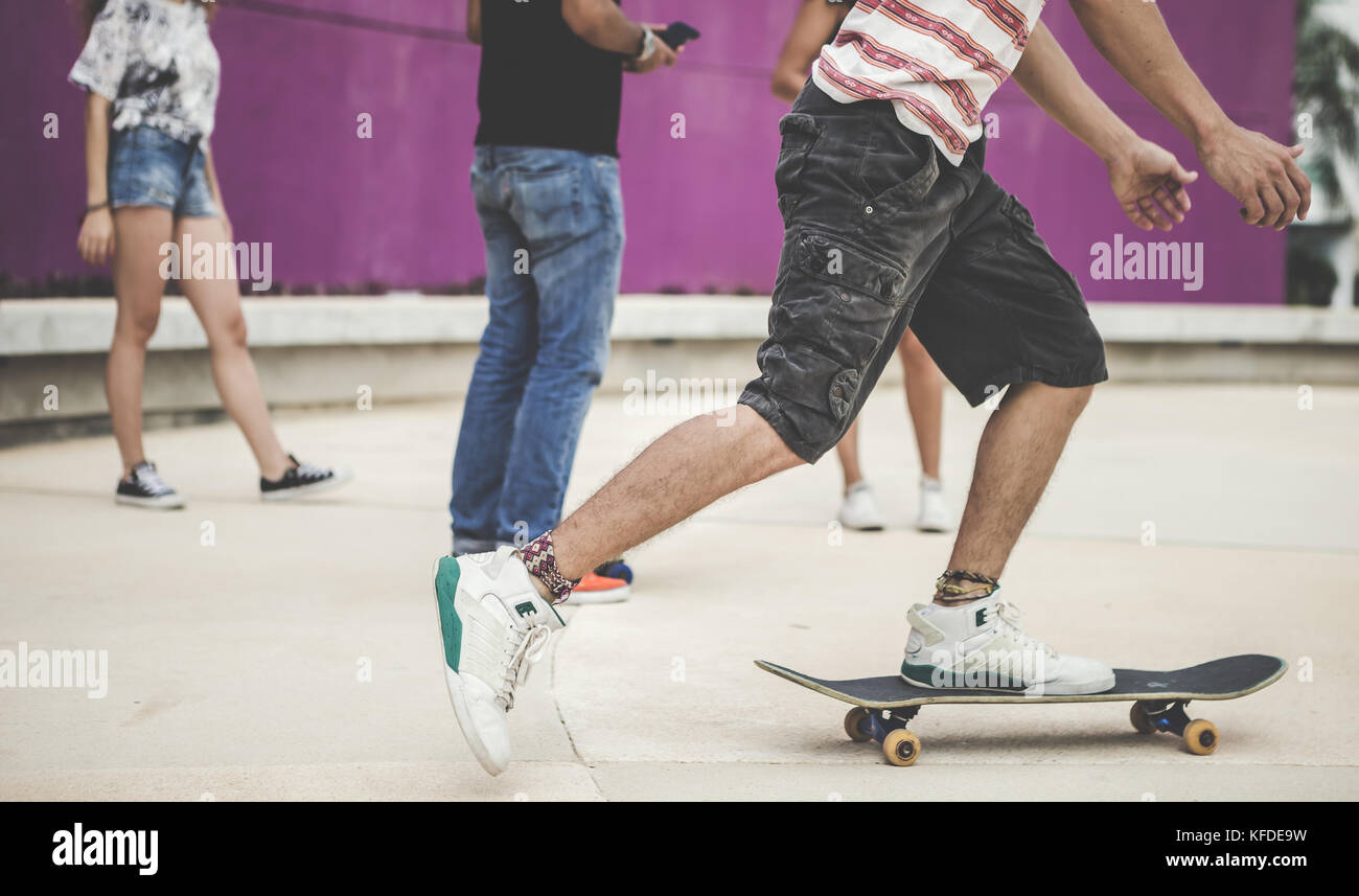 Close up of a group of people standing in a skate park and riding a ...