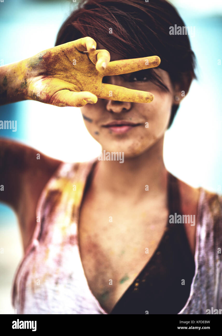 Young woman holding two paint-stained fingers in front of her face ...