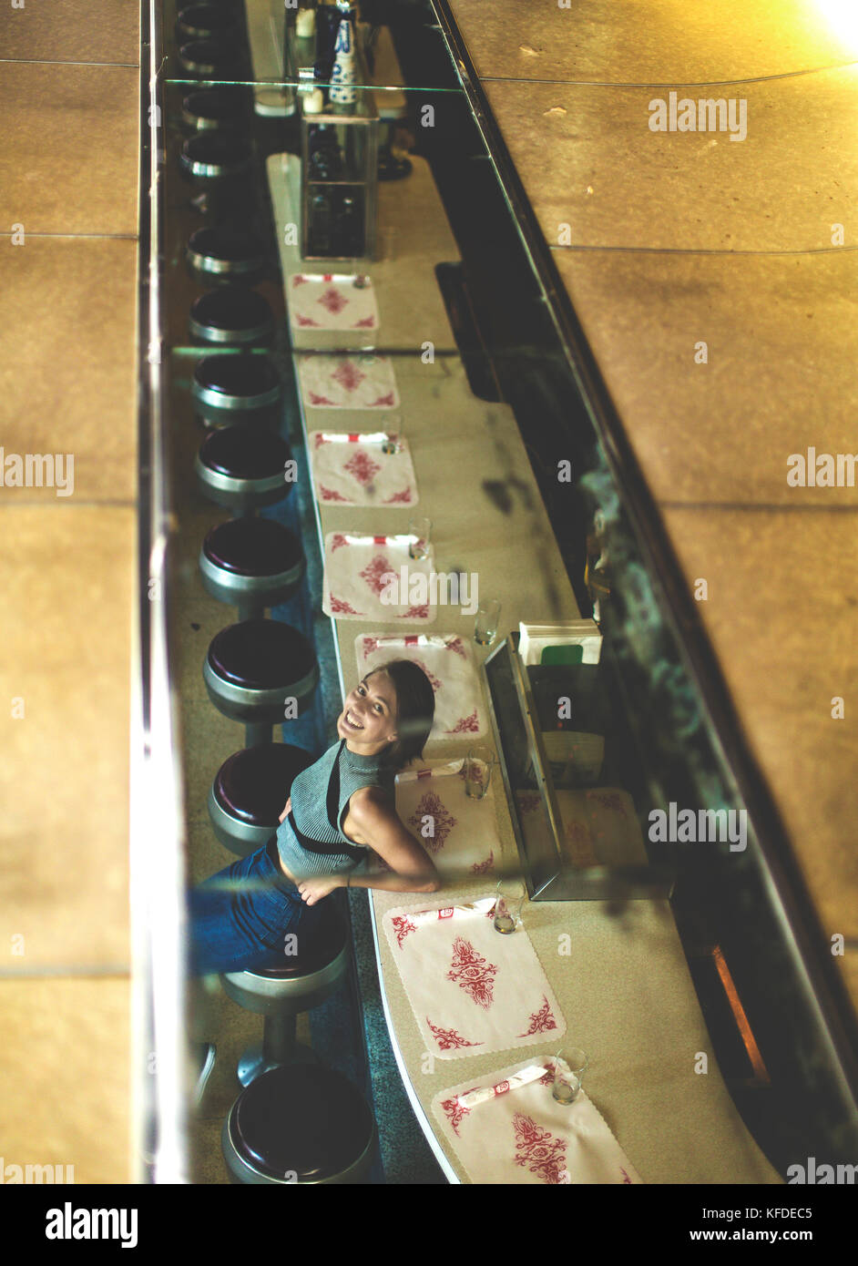 High angle view of woman sitting at a bar counter looking up at the ...