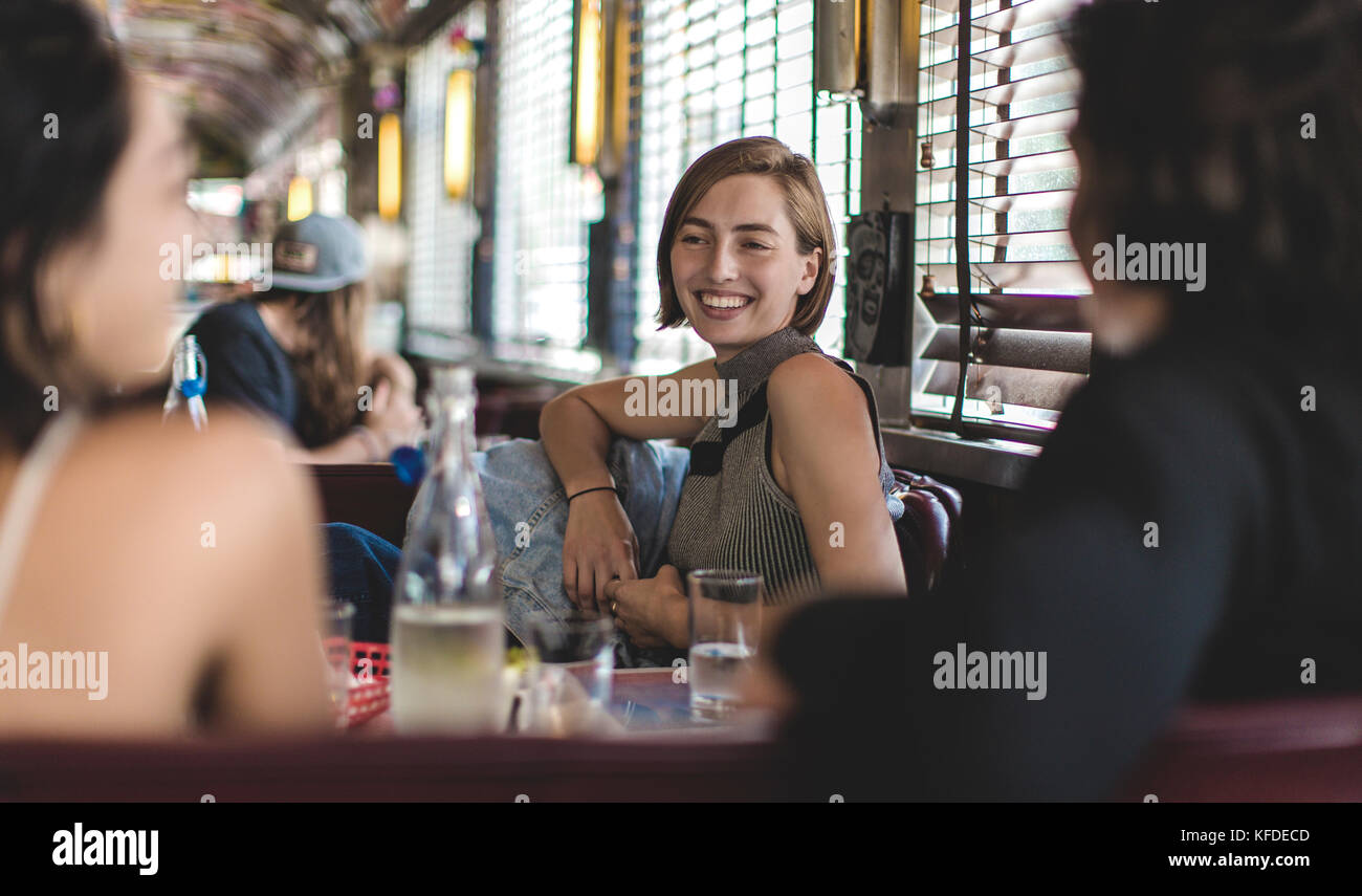 Smiling woman sitting with two friends in a booth in a diner Stock ...