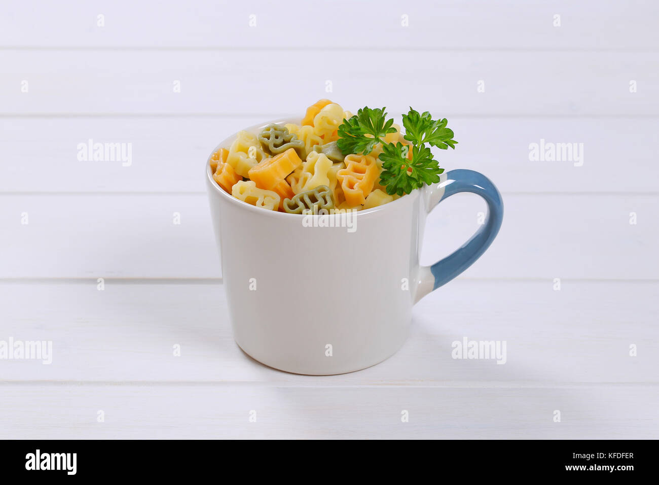 mug of cooked colored pasta on white wooden background Stock Photo - Alamy