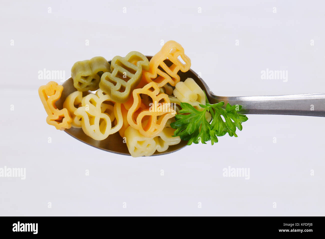 spoon of cooked colored pasta on white wooden background Stock Photo ...