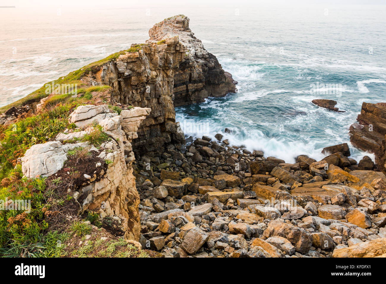 Rocky beach under a cliff at sunset Stock Photo - Alamy
