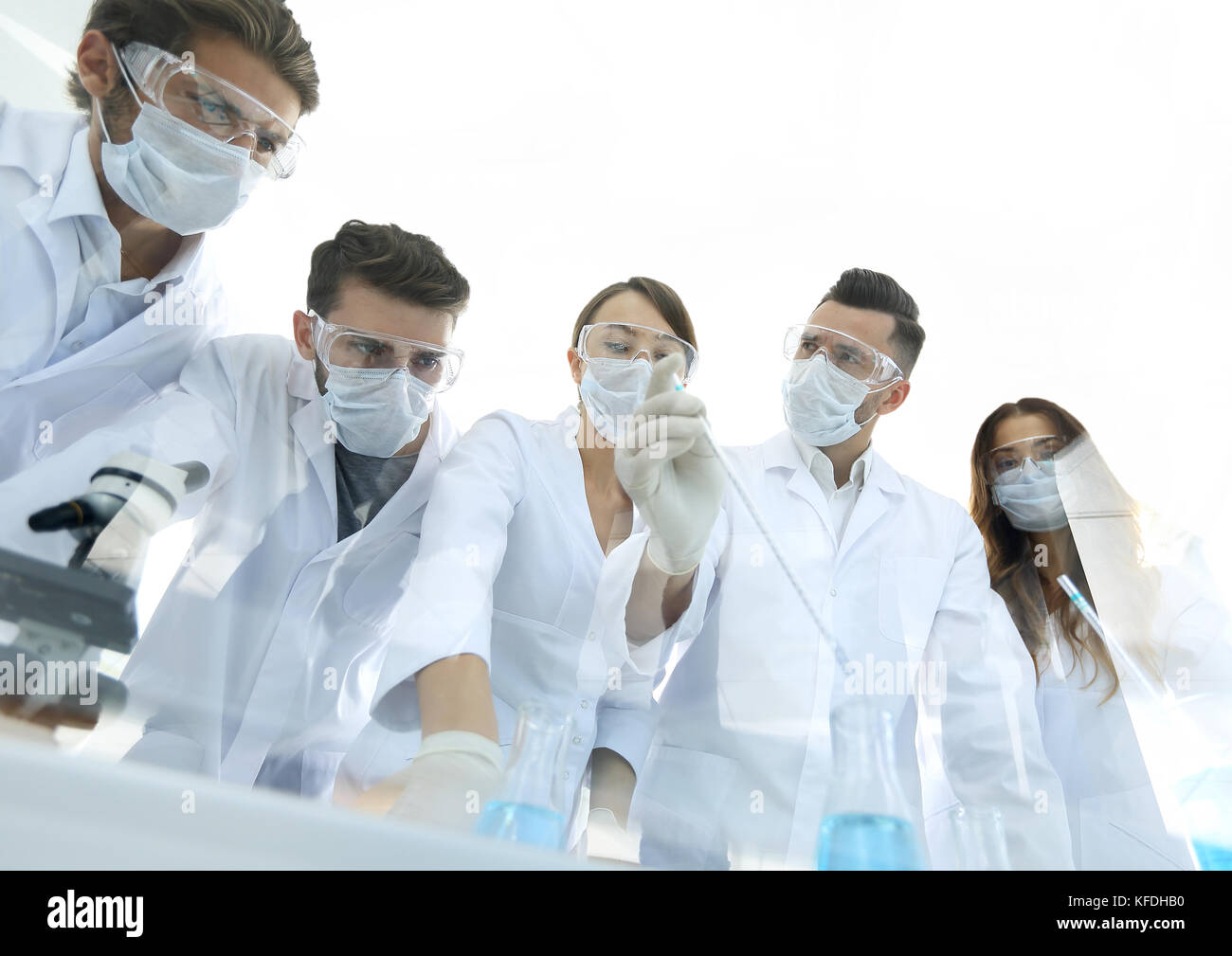 group of scientists working with test tubes and microscope in the ...