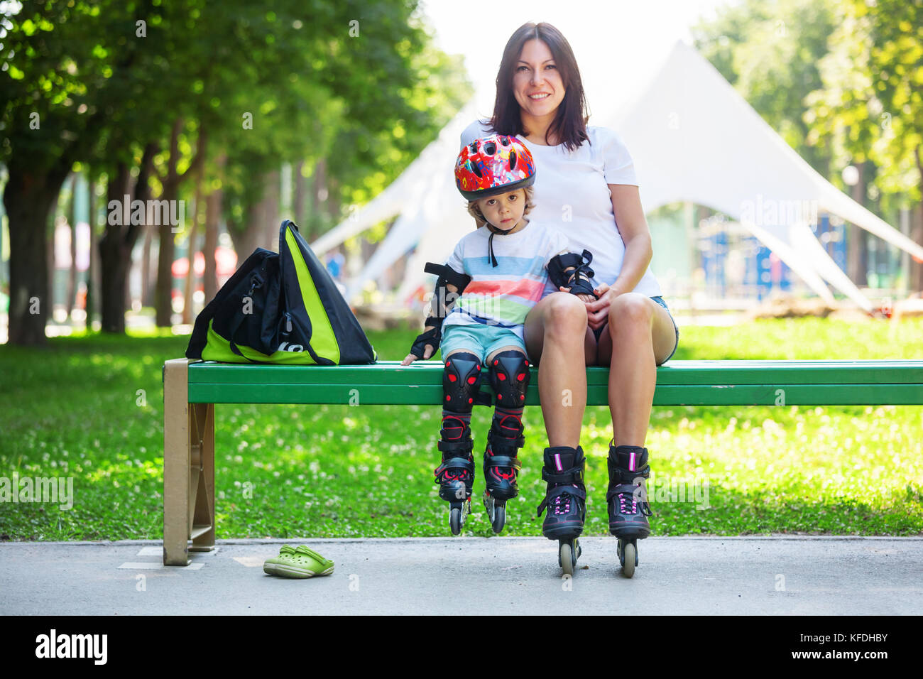 Portait of cute baby boy and his mom wearing inline skates sitting on ...