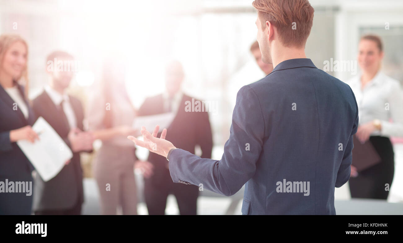 Successful business man standing with his staff in background at office ...
