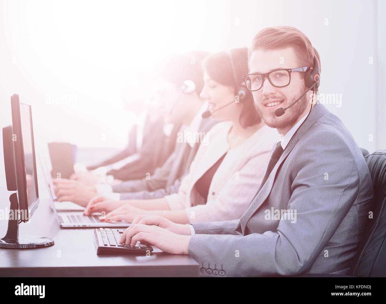 side view: operator in the call center looking at the camera and his ...