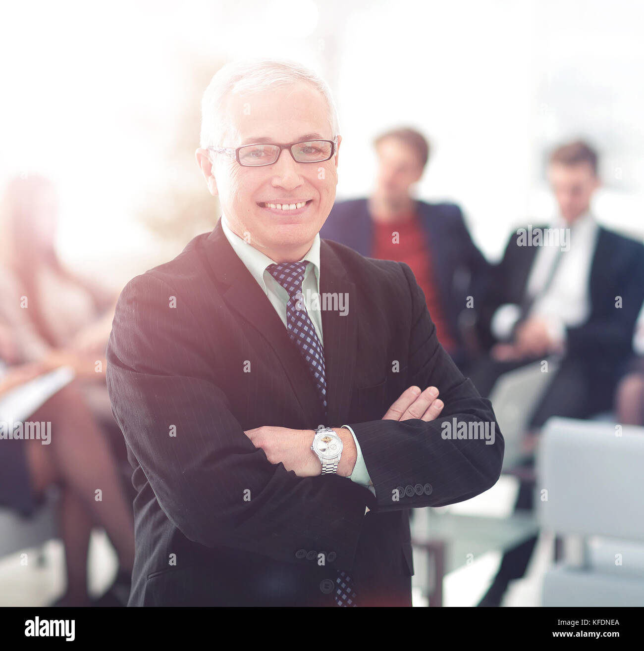 Successful business man standing with his staff in background at office ...