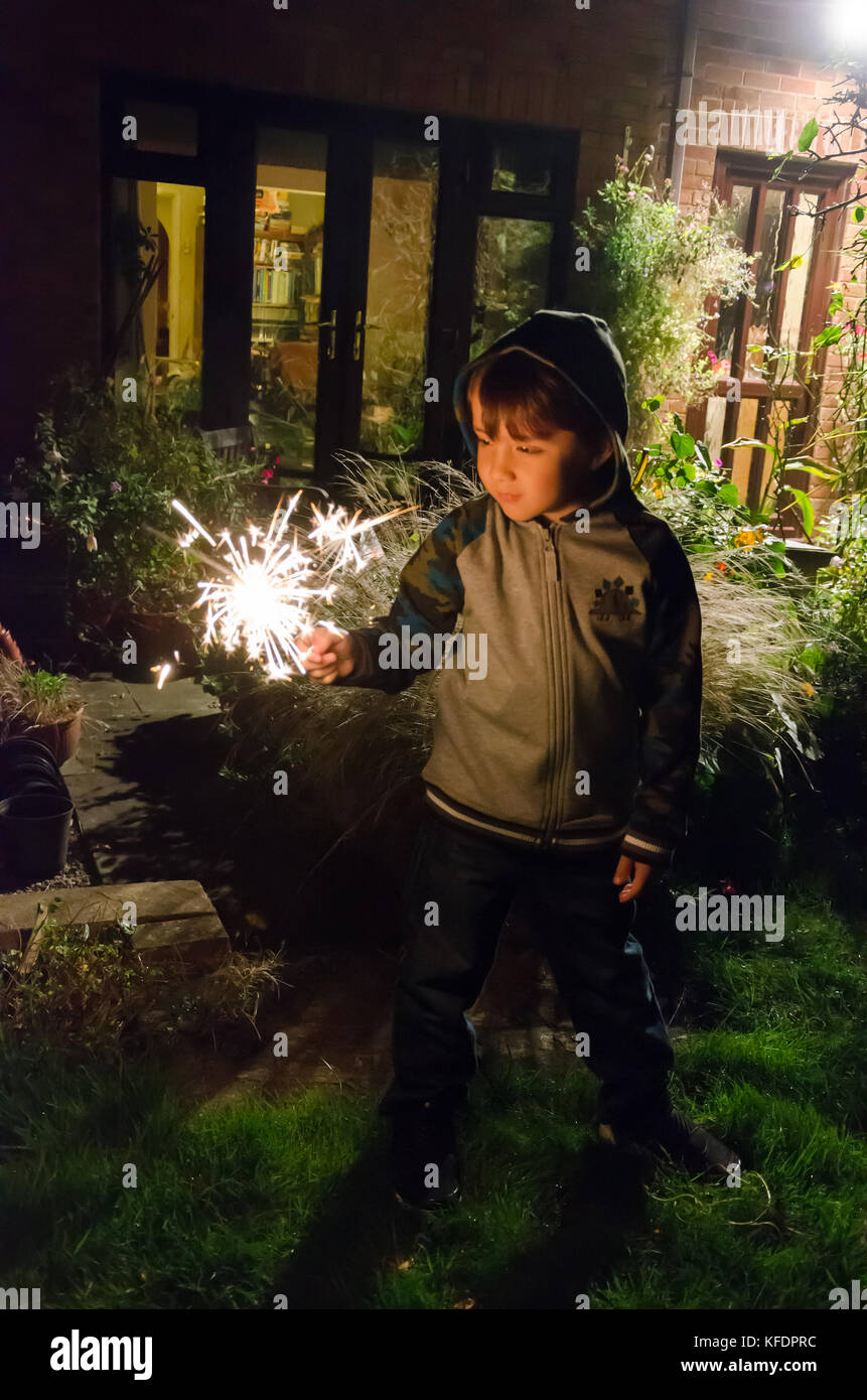A young boy playing with a sparkler in the back garden Stock Photo - Alamy